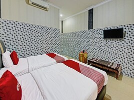 Quarto de hotel com cama, televisão e uma pequena mesa de madeira.