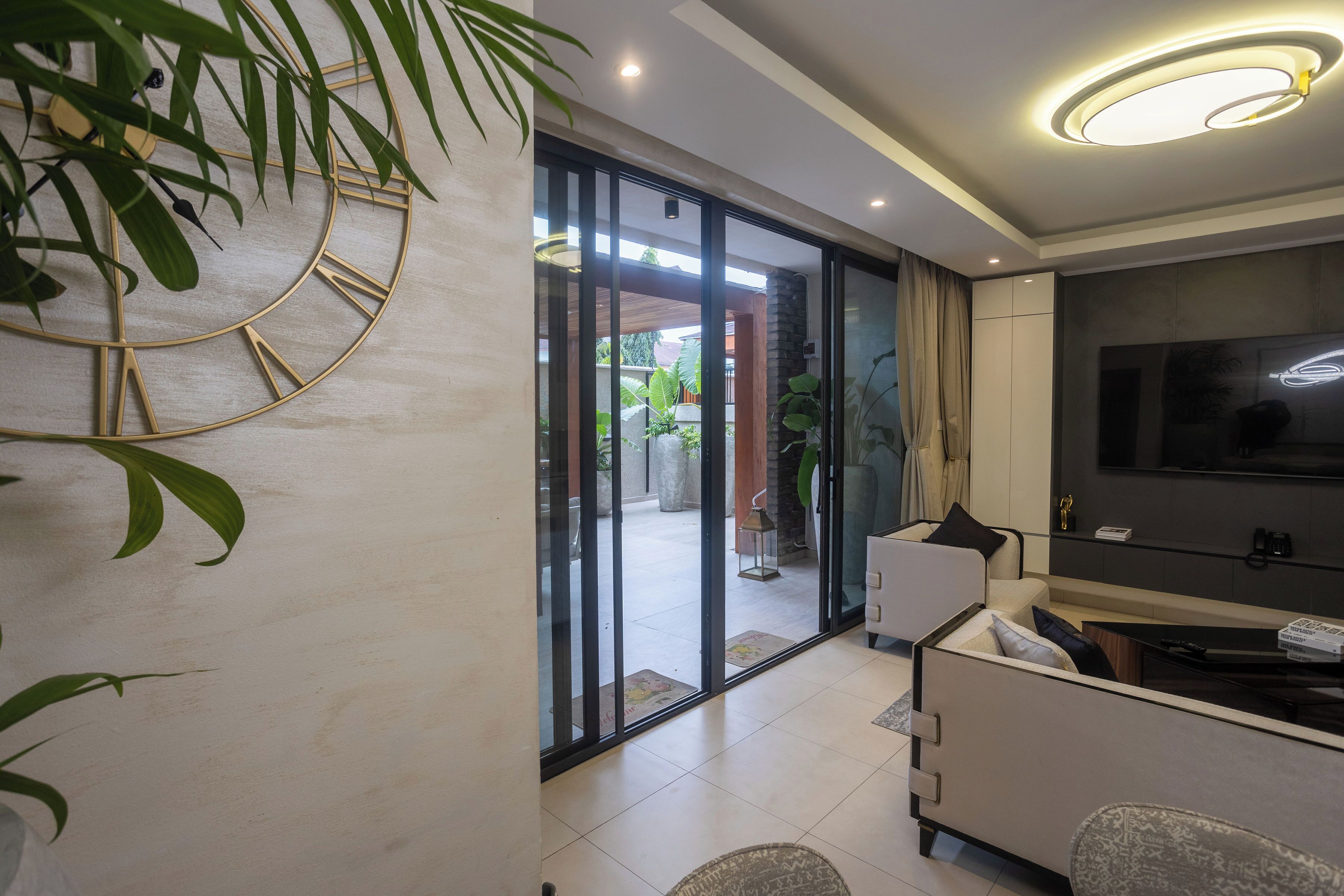 Sala de estar moderna com sofá, televisão e um objeto decorativo na parede.