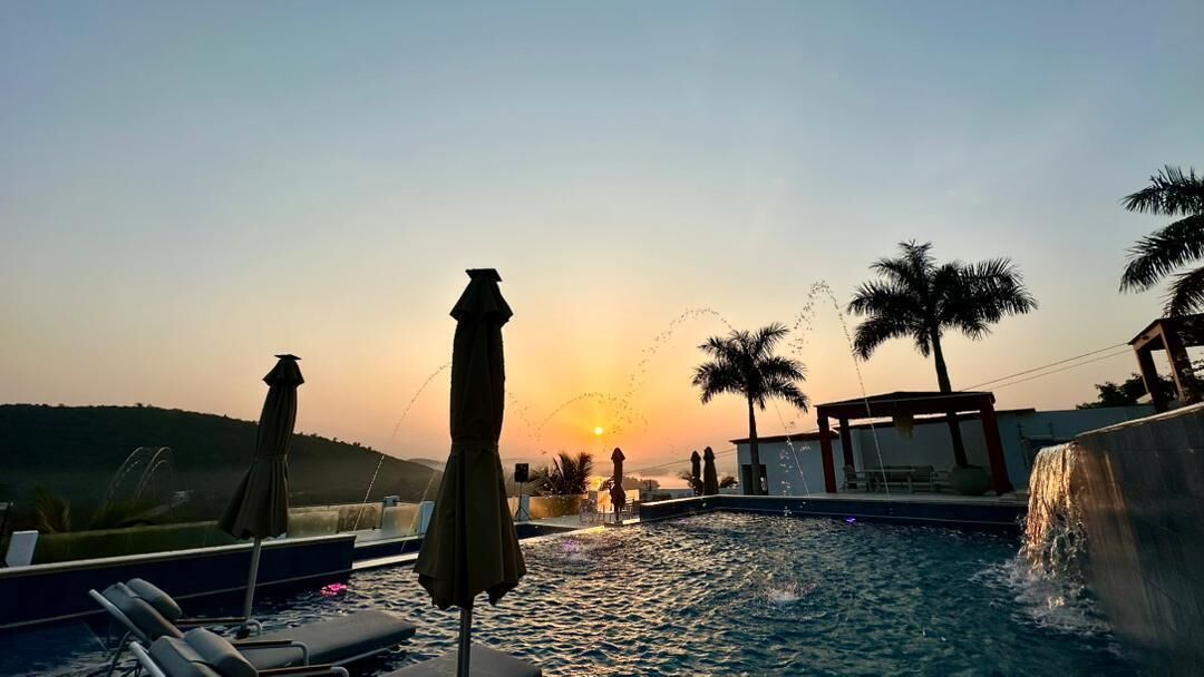 Uma área de piscina com espreguiçadeiras, guarda-sóis e uma cascata.