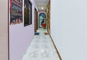Um corredor com piso de azulejos, um cartaz na parede e uma porta com painel de vidro.