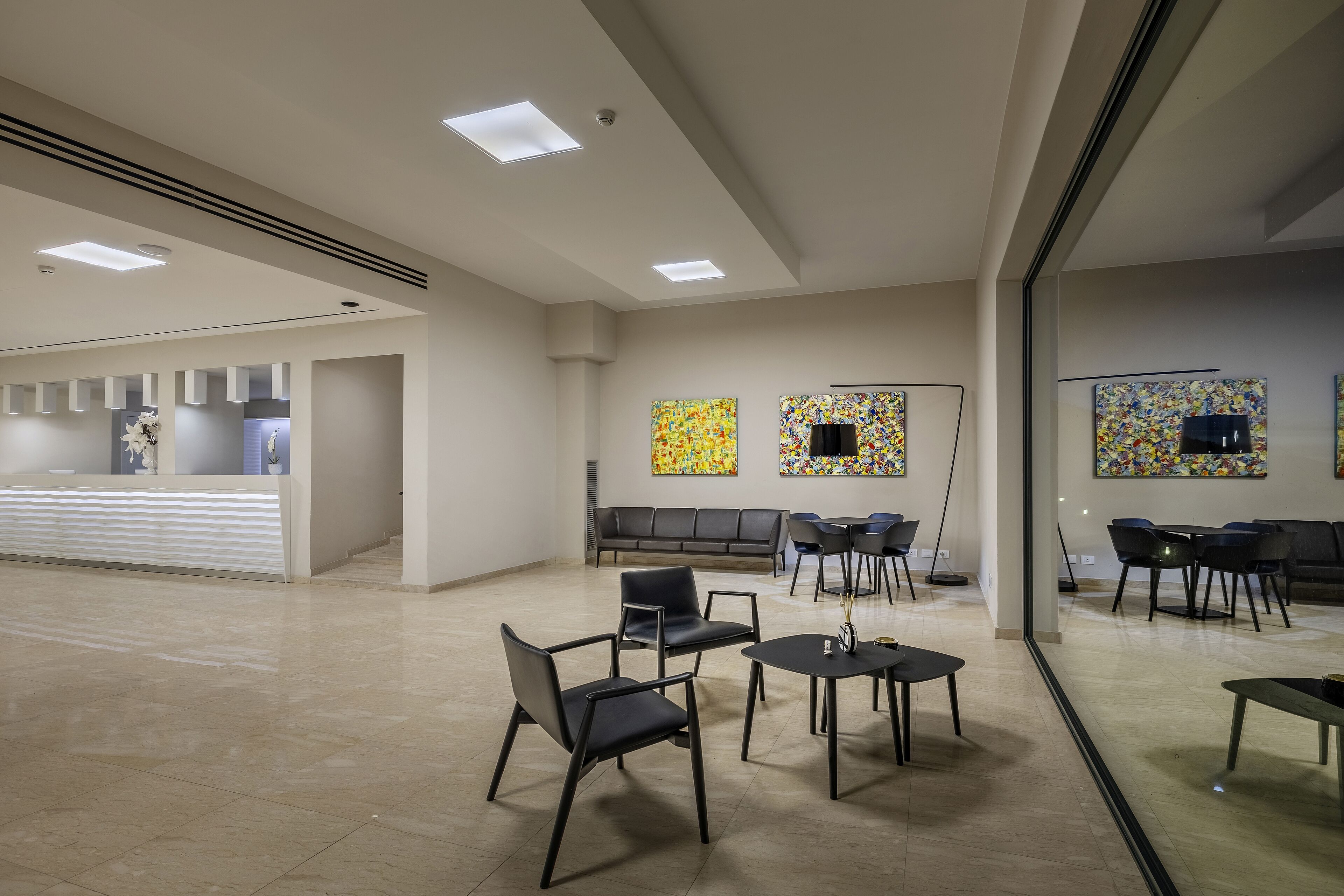 Um hall amplo com balcão de recepção, área de estar e obras de arte nas paredes.