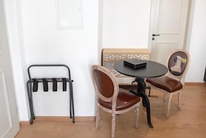 Uma pequena área de refeições com uma mesa redonda, duas cadeiras e uma cadeira preta com encosto.