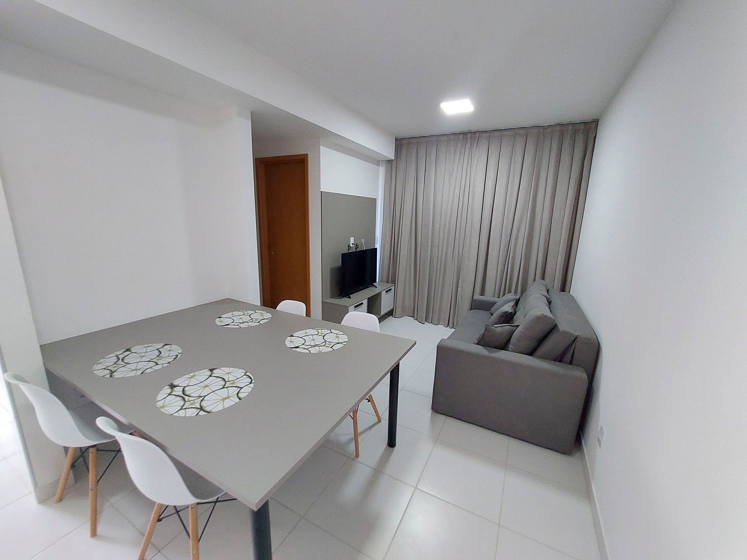 Um espaço de estar moderno com uma mesa de jantar, cadeiras, um sofá e uma televisão.