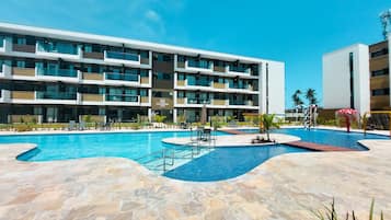 Um hotel com piscina, várias varandas e um céu azul límpido.
