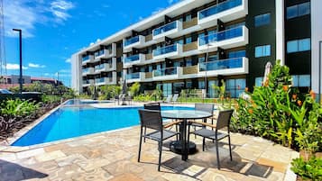 Um hotel moderno com piscina, área de estar externa e vegetação exuberante.