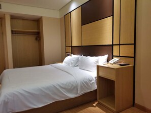 Quarto de hotel com cama, mesa de cabeceira e guarda-roupa.