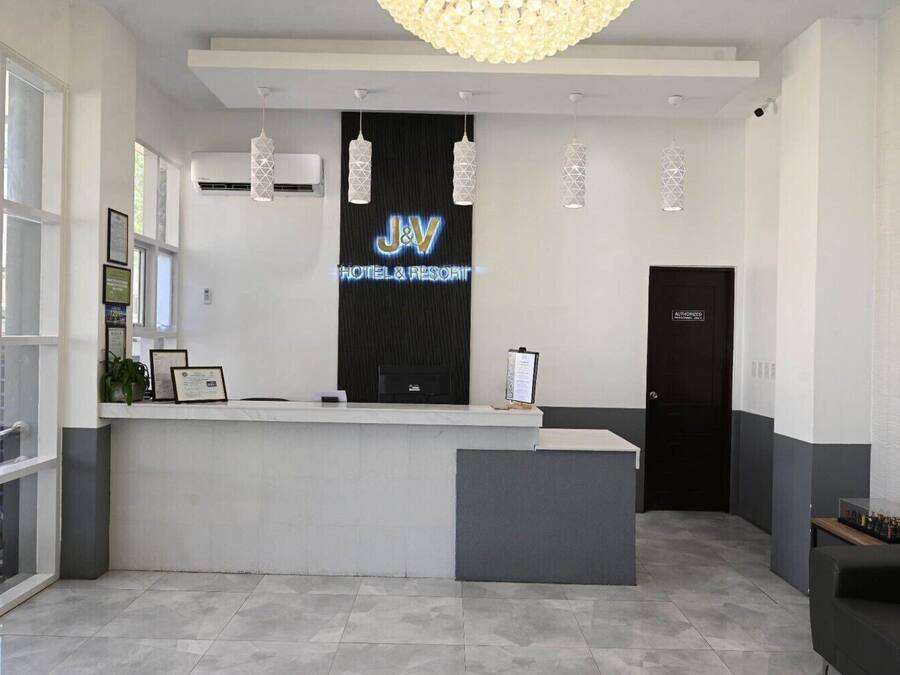 Uma área de recepção de hotel com design moderno, com balcão de recepção, unidades de ar condicionado e um lustre.