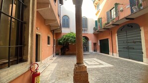 Um pátio externo com um extintor de incêndio, um pilar de tijolo e um chão ladrilhado.