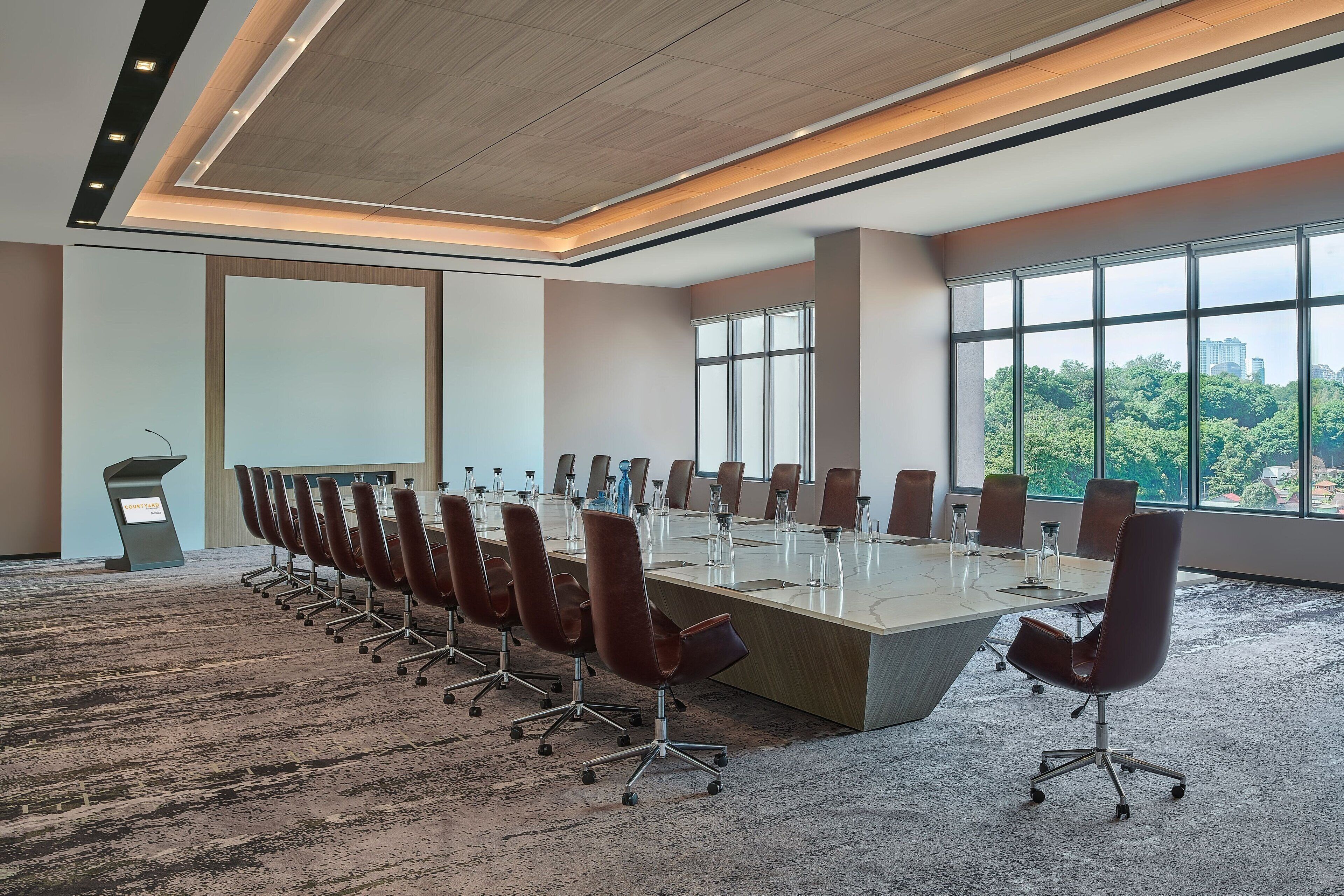 Uma sala de conferências com uma mesa comprida, várias cadeiras e um pódio.