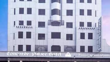 Hotel com fachada moderna, vários andares e entrada destacada.