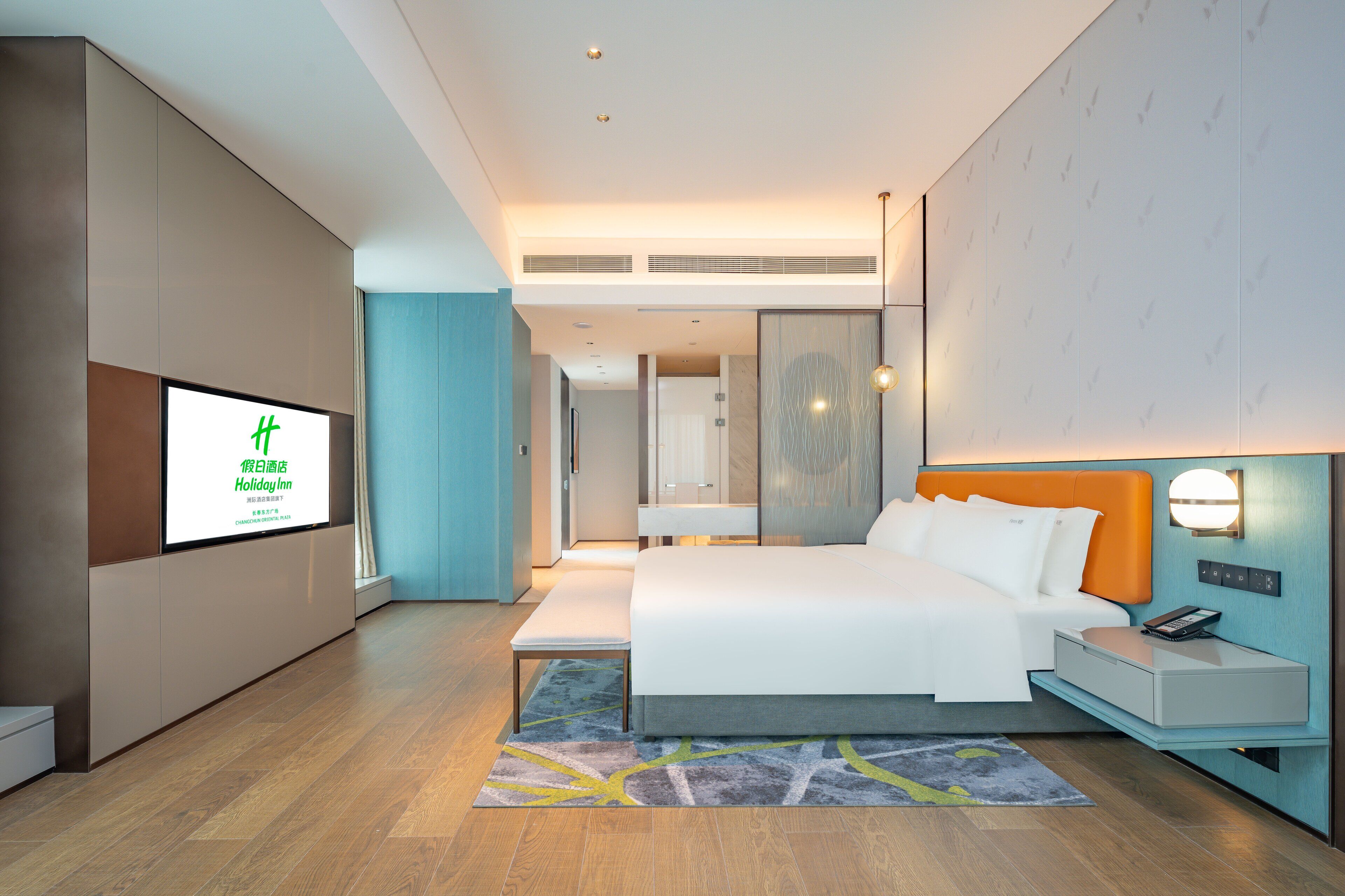 Quarto de hotel moderno com uma cama grande, mesa de cabeceira e televisão de tela plana fixada na parede.