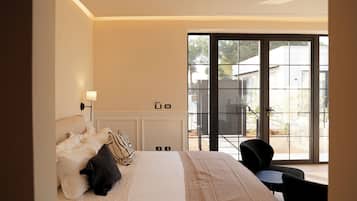 Quarto de hotel com uma cama, uma cadeira e vista para o exterior através de uma porta de vidro.