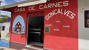 Um edifício vermelho com uma placa que diz "Casa de Carnes Goncalves" e o logotipo de "Lingua Artesanal".