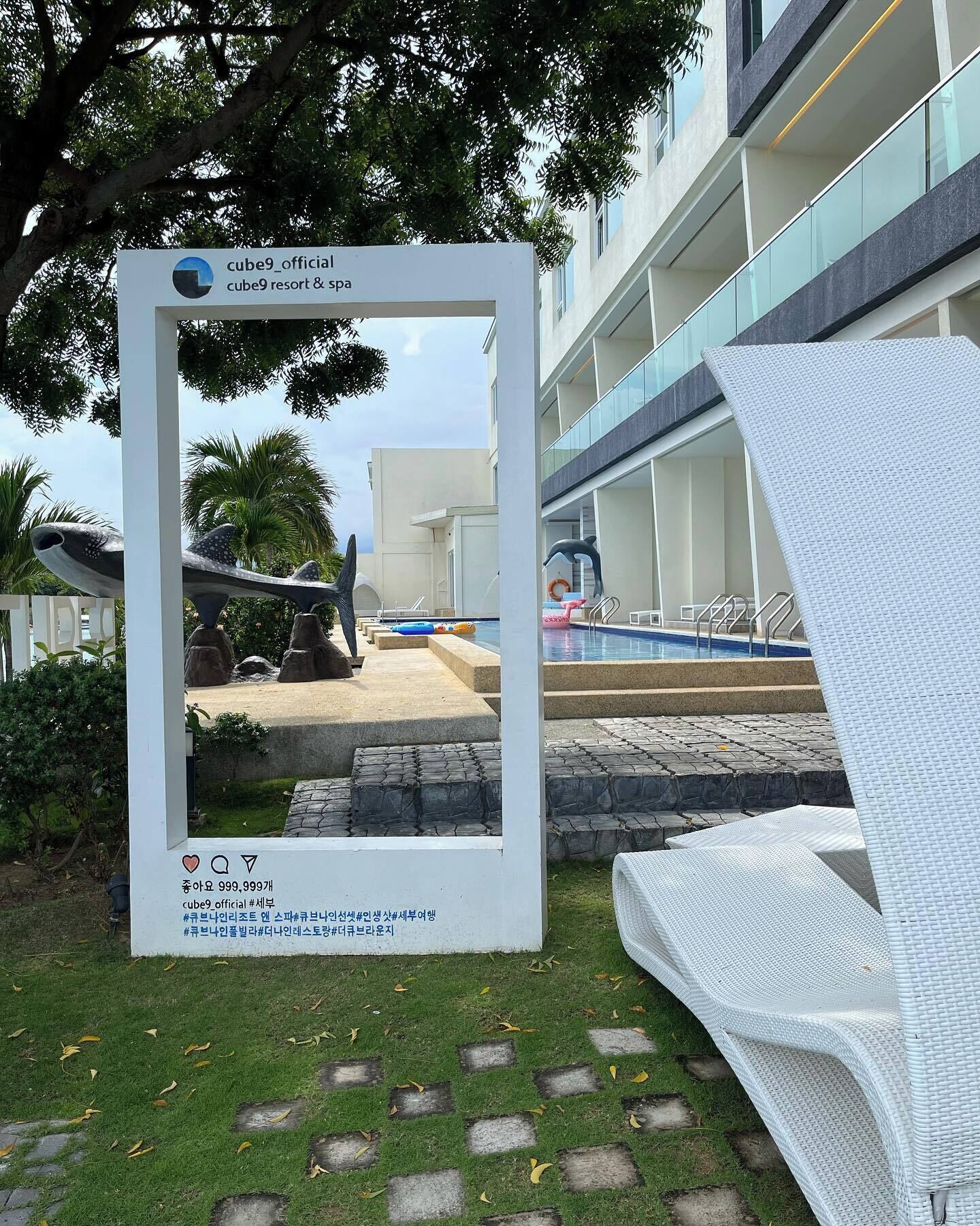 Um edifício moderno com piscina, uma grande placa branca e uma escultura.