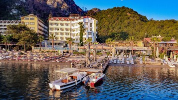 Um hotel à beira-mar com vários andares, área de estar ao ar livre e um cais com barcos.