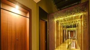 Um corredor com portas de madeira, piso polido e parede decorativa com plantas penduradas.