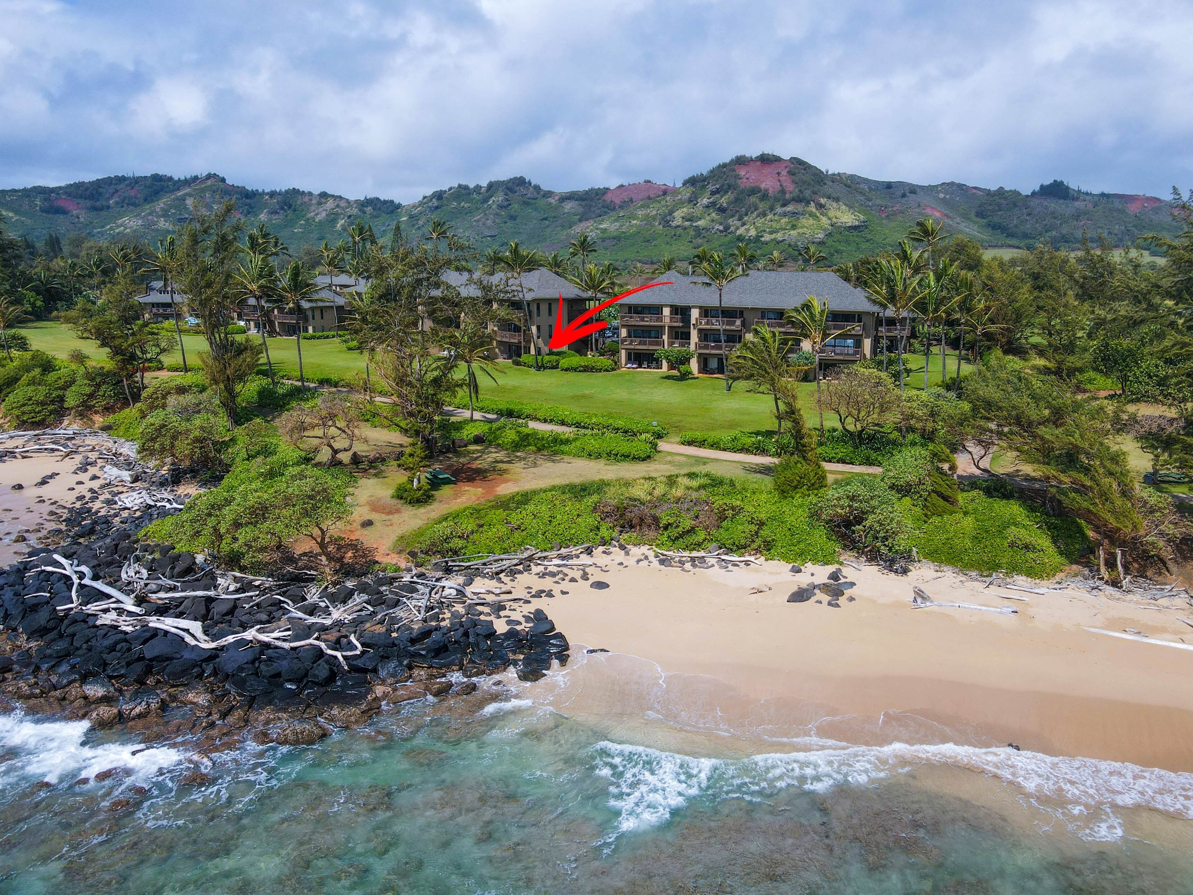 Um hotel à beira-mar com vários edifícios, um litoral rochoso e montanhas ao fundo.