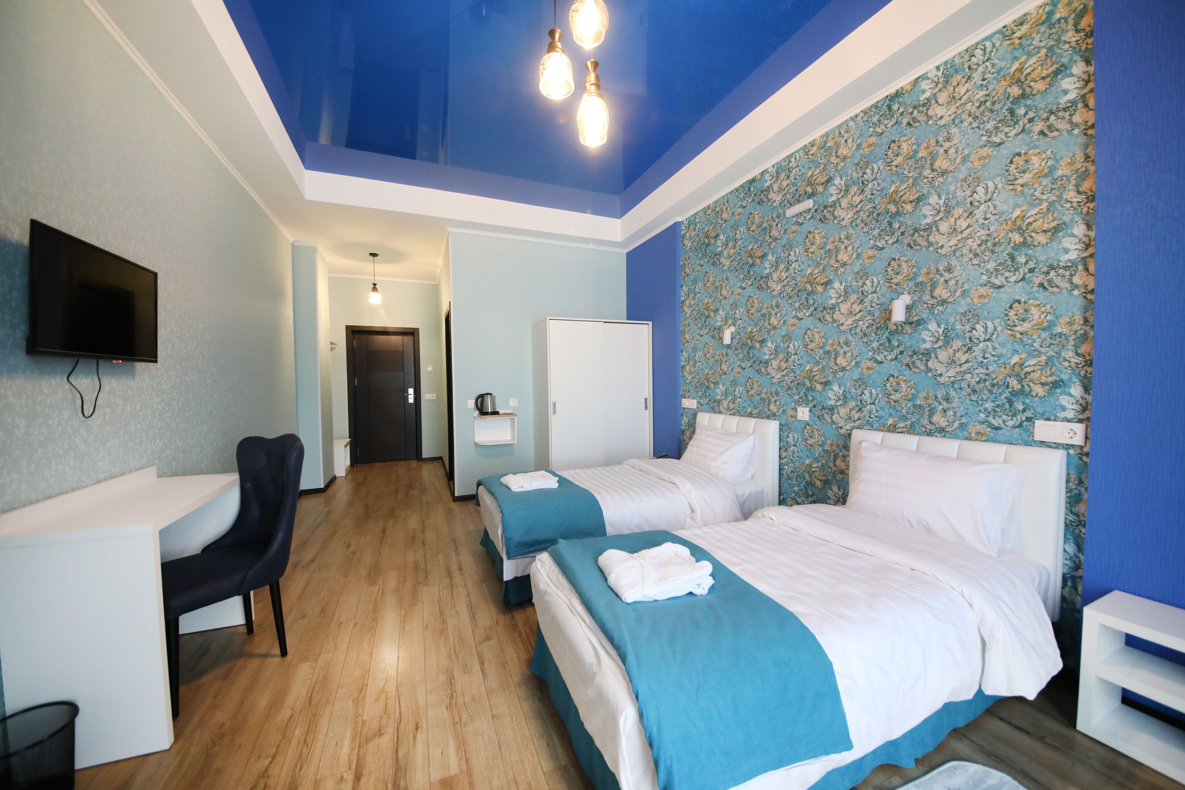 Quarto de hotel com duas camas, uma escrivaninha e uma televisão.