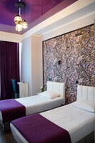 Quarto de hotel com duas camas, uma escrivaninha e uma cadeira.