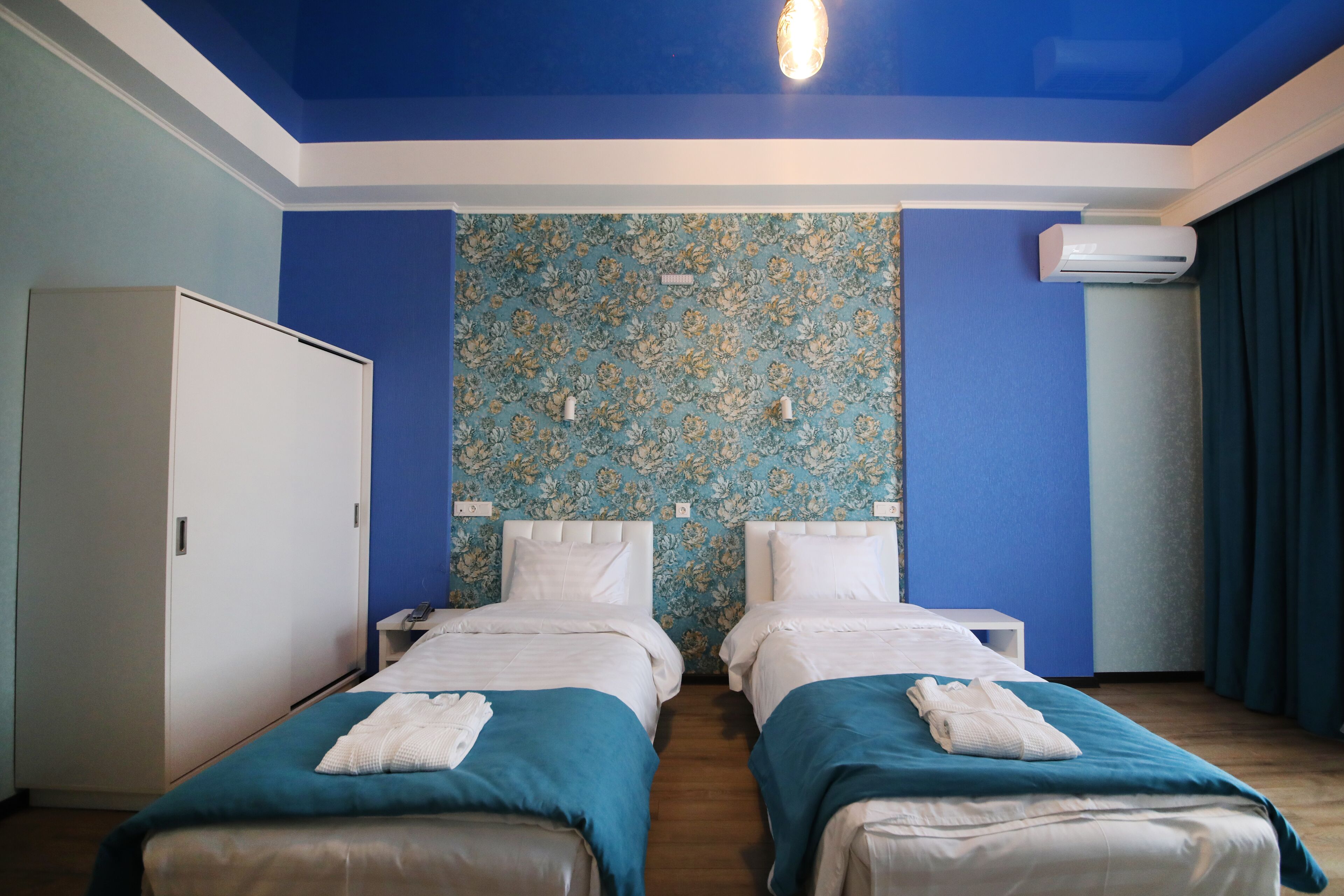 Quarto de hotel com duas camas, um guarda-roupa e ar condicionado.