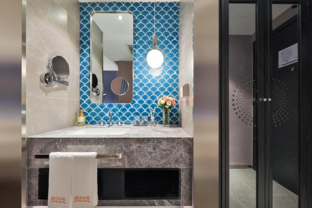 Casa de banho com parede azul estampada, espelho, lavatório e porta-toalhas.