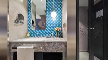 Casa de banho com parede azul estampada, espelho, lavatório e porta-toalhas.
