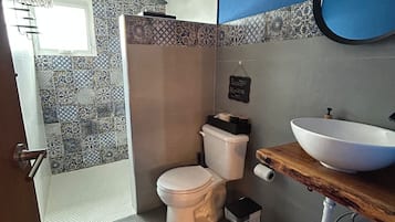 Uma casa de banho moderna com sanita, lavatório e chuveiro.