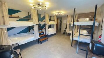 Quarto de dormitório com beliches, escada, escrivaninha e cadeira.