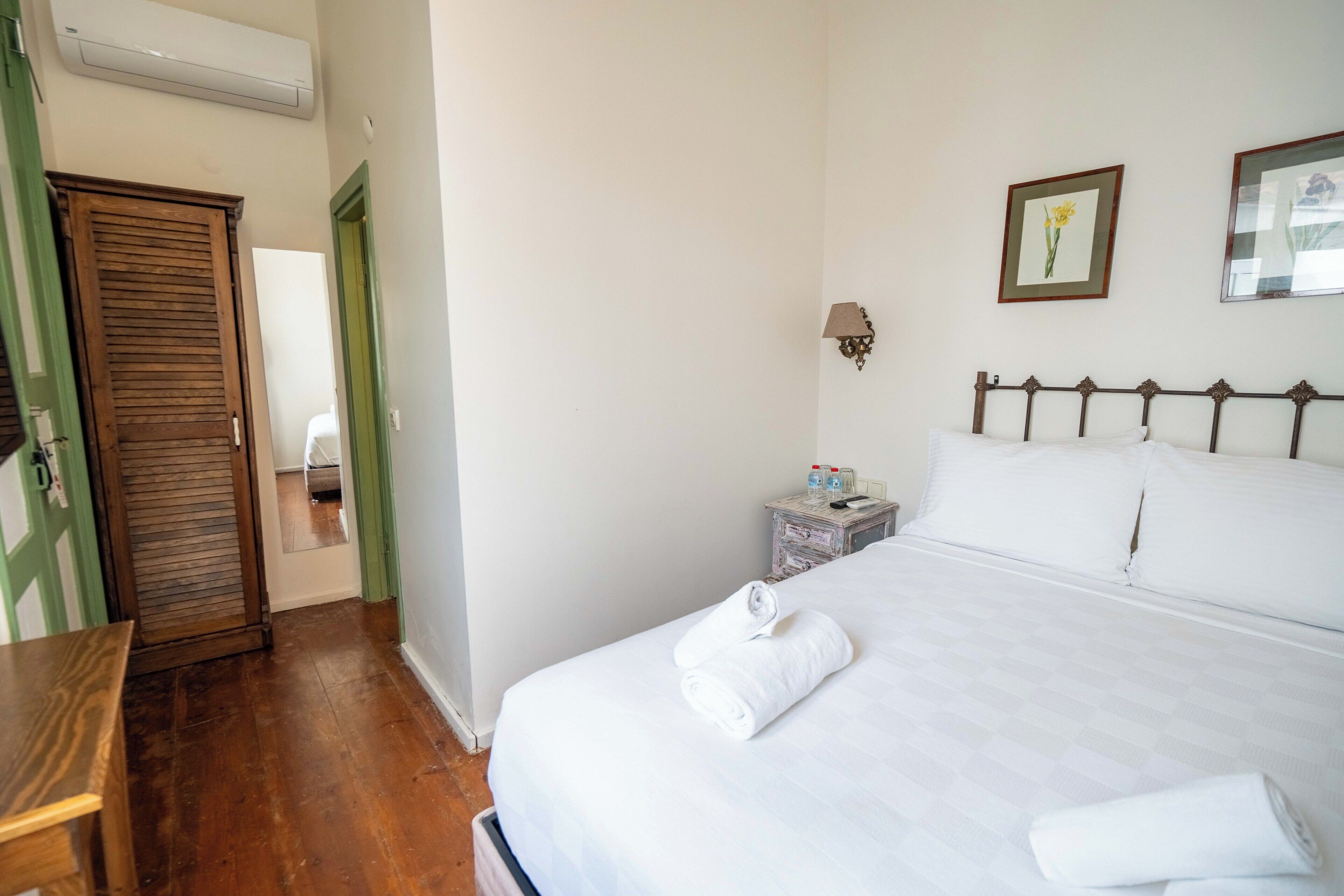 Quarto de hotel com cama de madeira, mesa de cabeceira, luminária e um quadro na parede.