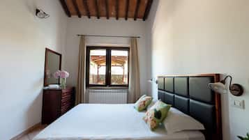 Quarto com uma cama grande, cômoda, espelho e janela com cortinas.