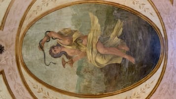 Afresco no teto, com moldura circular, retratando uma figura vestida com roupa esvoaçante.