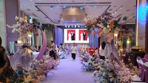 Corredor de hotel com decorações florais e um palco no final.