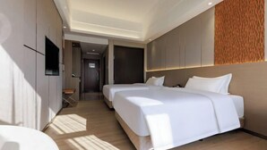 Quarto de hotel moderno com duas camas, TV de tela plana e uma parede de destaque em madeira.