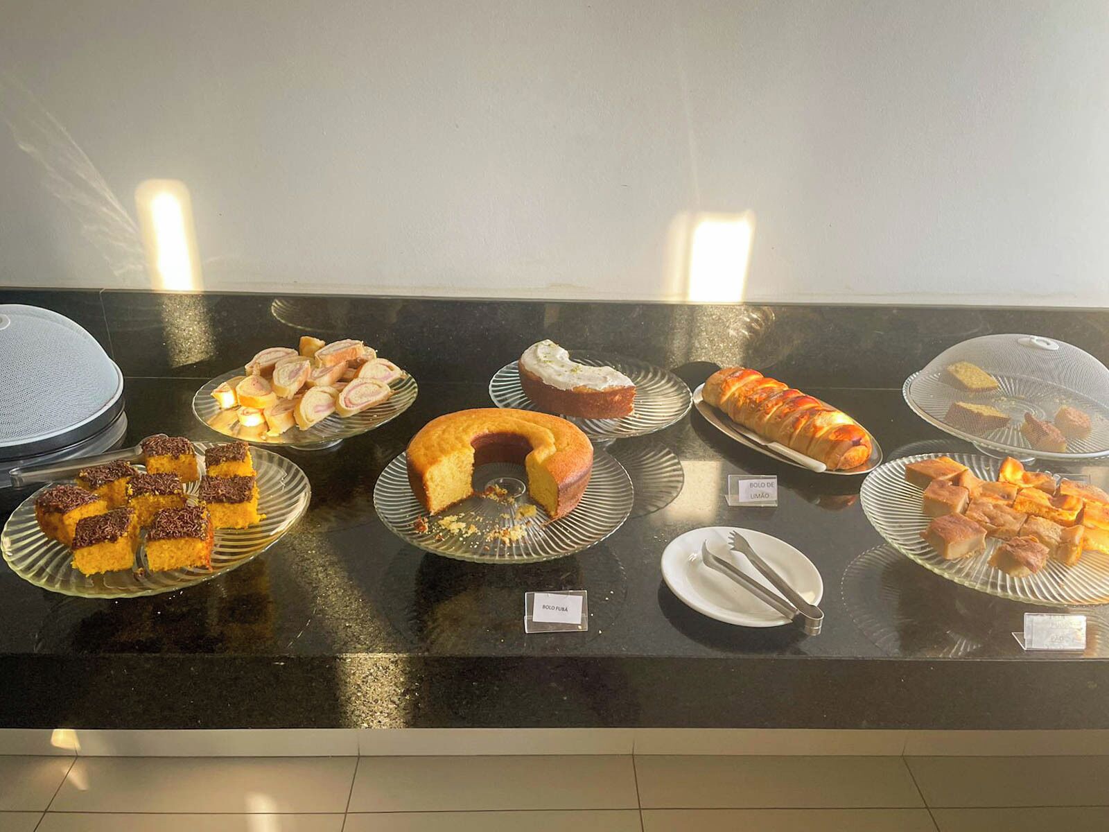 Um balcão de buffet com diversos produtos de panificação e sobremesas.
