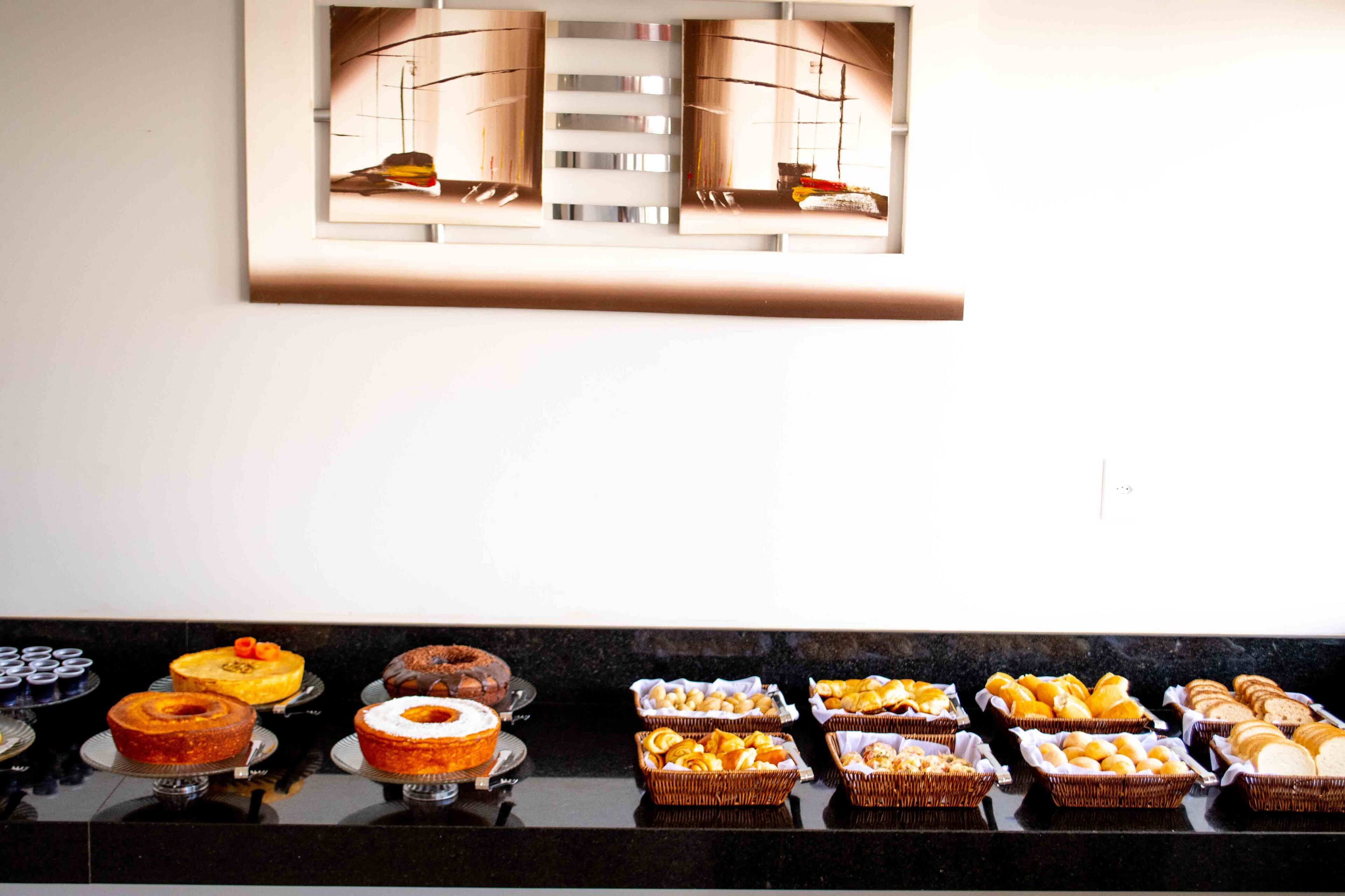Buffet com diversos pães e doces.