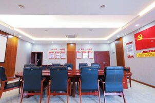 Uma sala de conferência com uma mesa comprida, cadeiras azuis e banners vermelhos nas paredes.