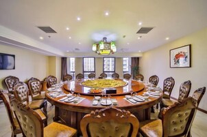 Uma sala de conferências com uma mesa redonda, cadeiras e um candelabro.