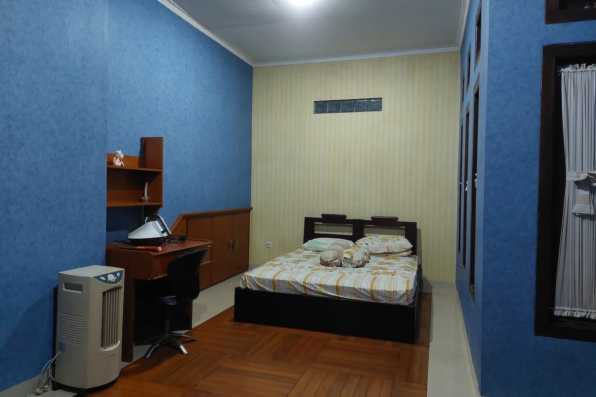 Um quarto com uma cama, uma escrivaninha e uma cadeira.