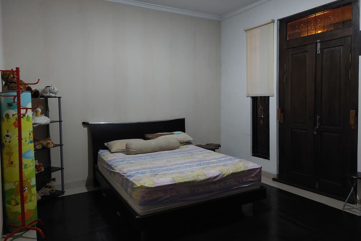 Quarto com cama, prateleira com brinquedos, guarda-roupa e janela com persianas.