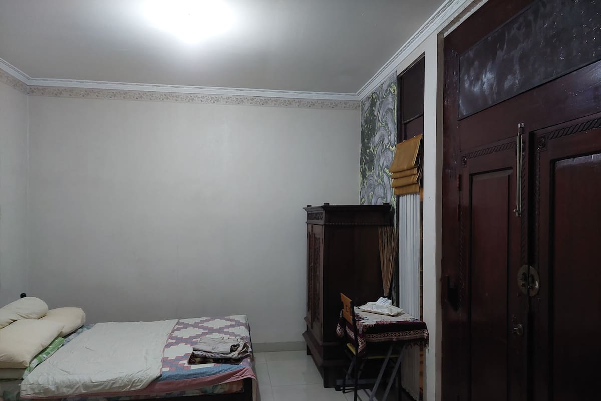 Quarto com cama, escrivaninha e guarda-roupa.