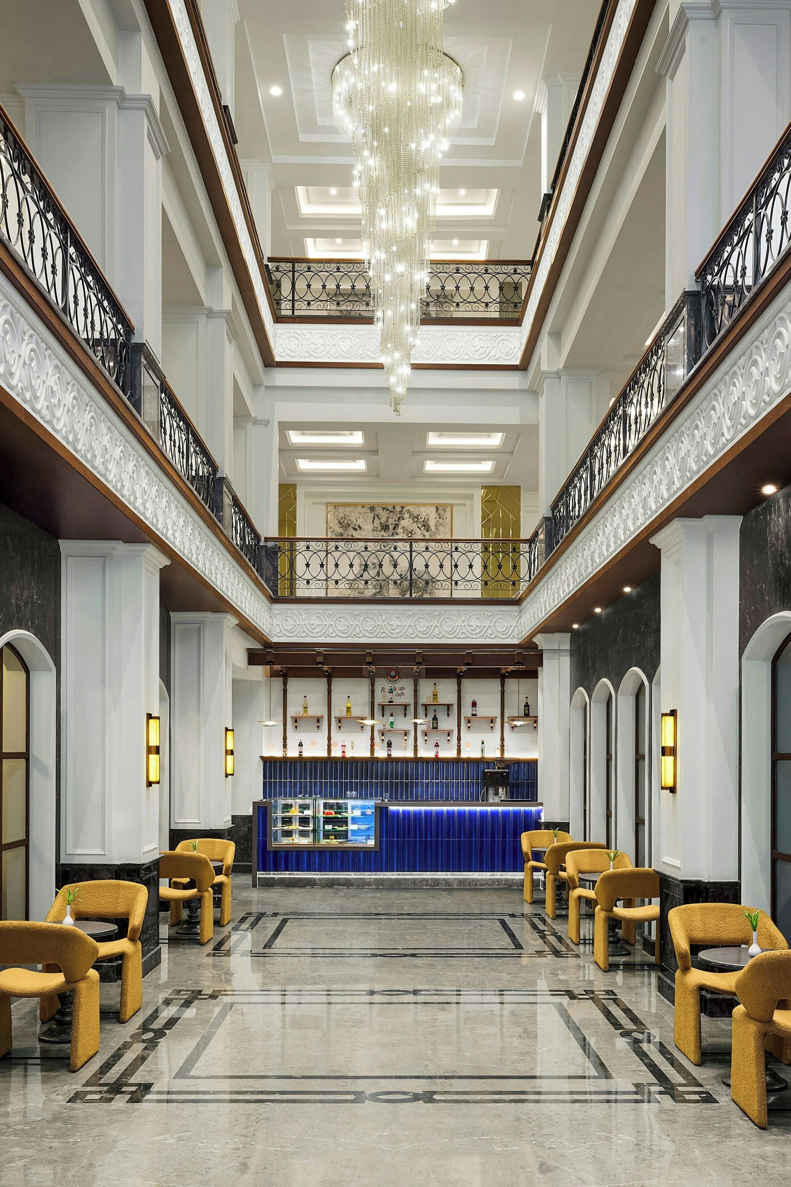 Um hall amplo com uma receção central, lustres e um mezanino com grades.
