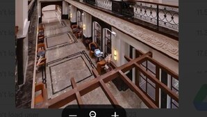 Um hall de hotel em vários níveis, com lustres, piso de mármore e uma varanda com grades elaboradas.