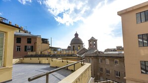 Terraço no telhado com guarda-corpo, com vista para um edifício histórico com cúpula e campanário.