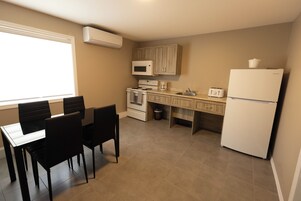 Uma cozinha compacta com mesa, cadeiras, micro-ondas, fogão, frigorífico e armários.