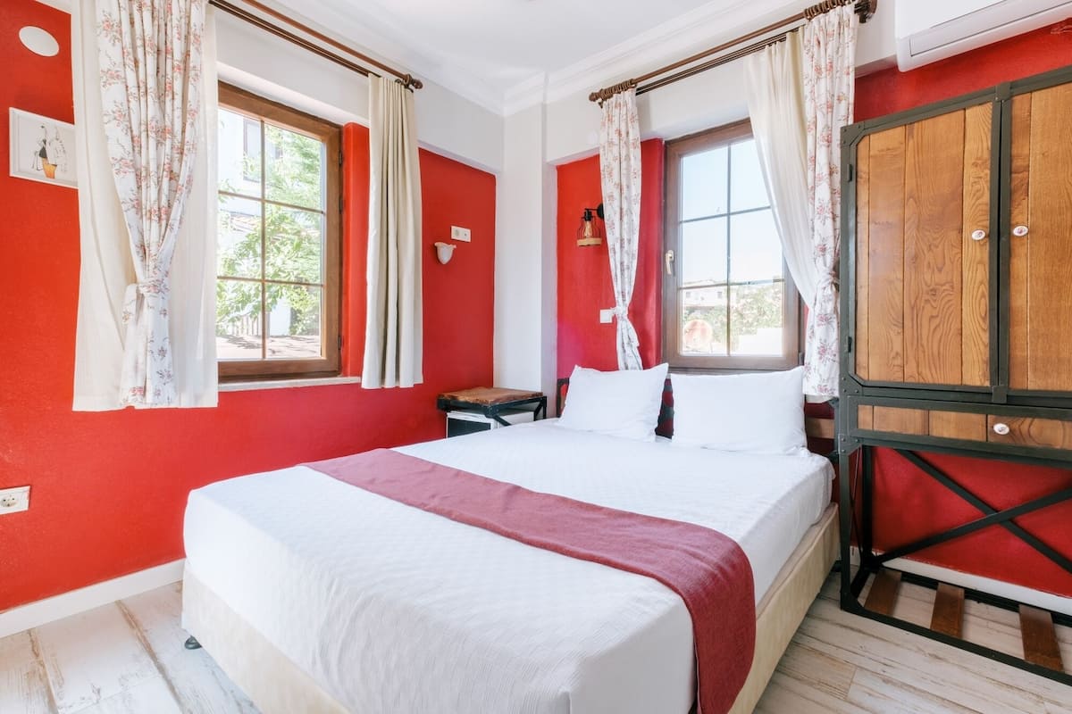 Um quarto com uma cama, um guarda-roupa de madeira e uma janela com cortinas.