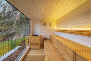 Uma sauna com bancos de madeira, uma pequena mesa e um aquecedor fixado na parede.