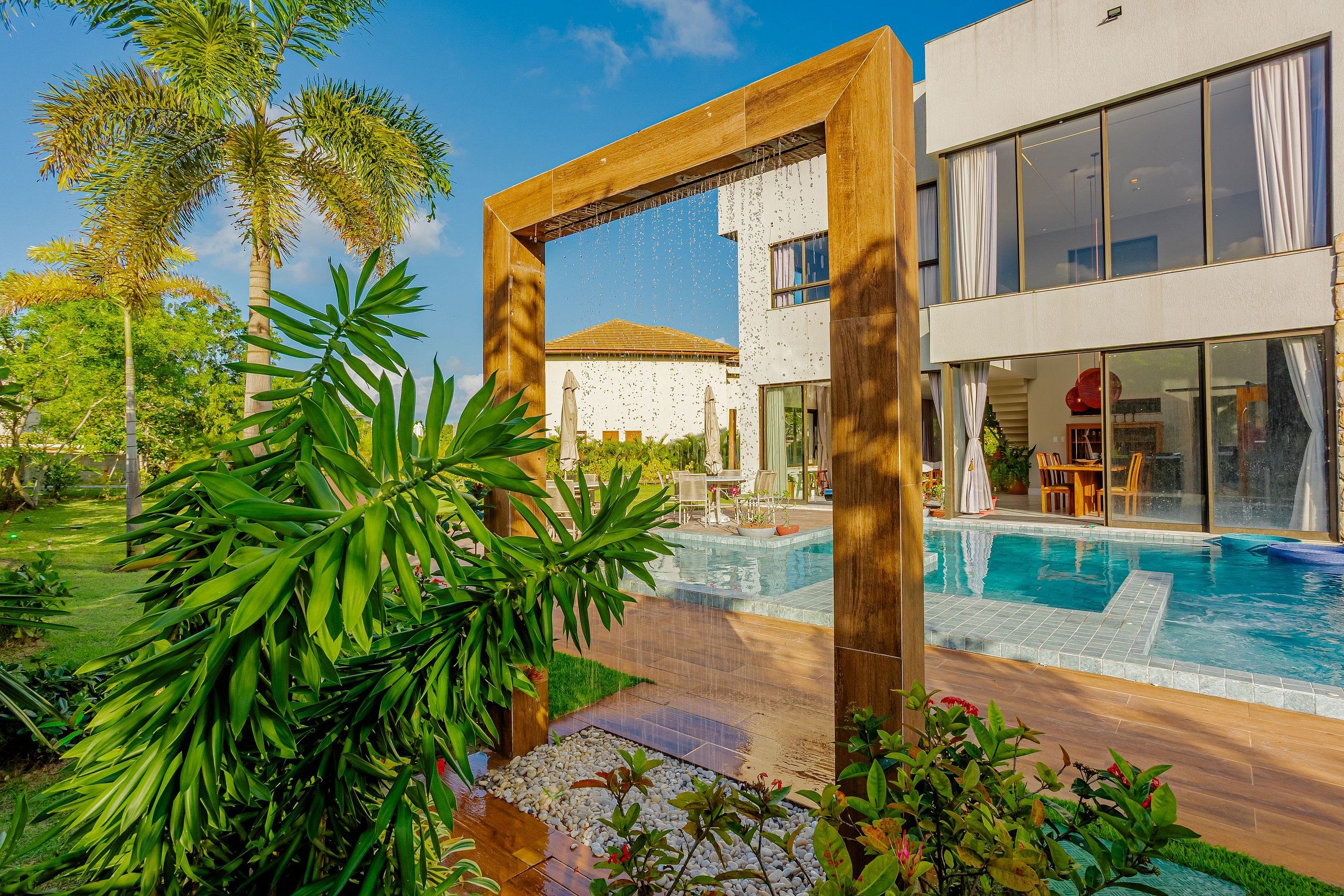 Um edifício moderno com piscina, cercado por vegetação exuberante e palmeiras.