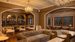 Um interior luxuoso com um imponente candelabro, espaço de bar e assentos confortáveis.