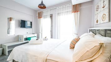 Quarto moderno com uma cama grande, uma televisão, uma toucador e uma janela com cortinas.