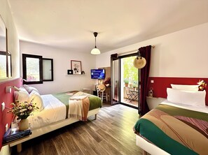 Quarto de hotel com duas camas, televisão, mesa pequena com uma cadeira, janela e porta para área externa.